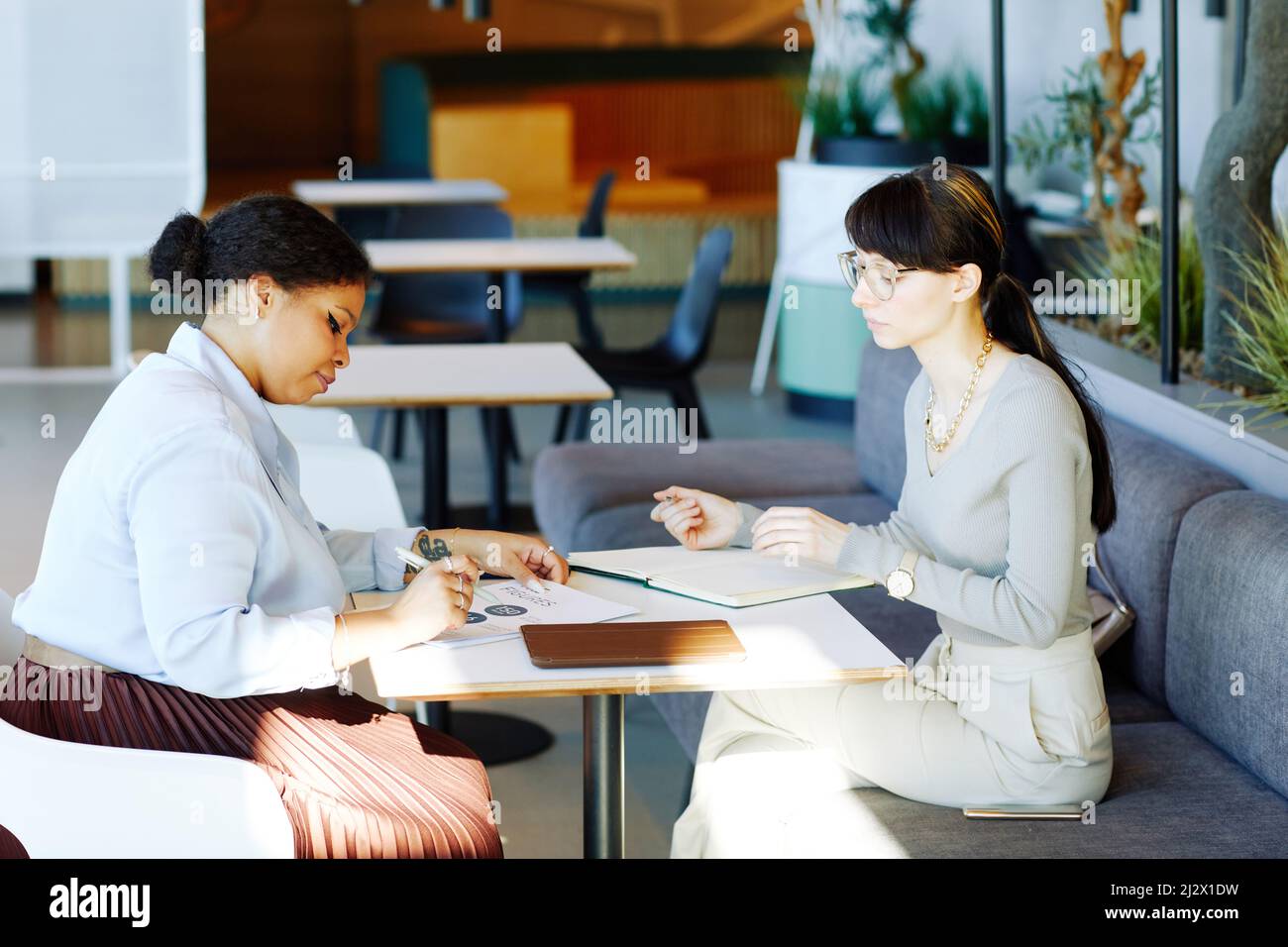 Side view portrait of two female business partners discussing project ...