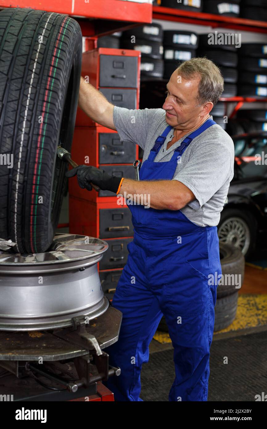 Qualified mechanic of service station straightening rim and repairing ...