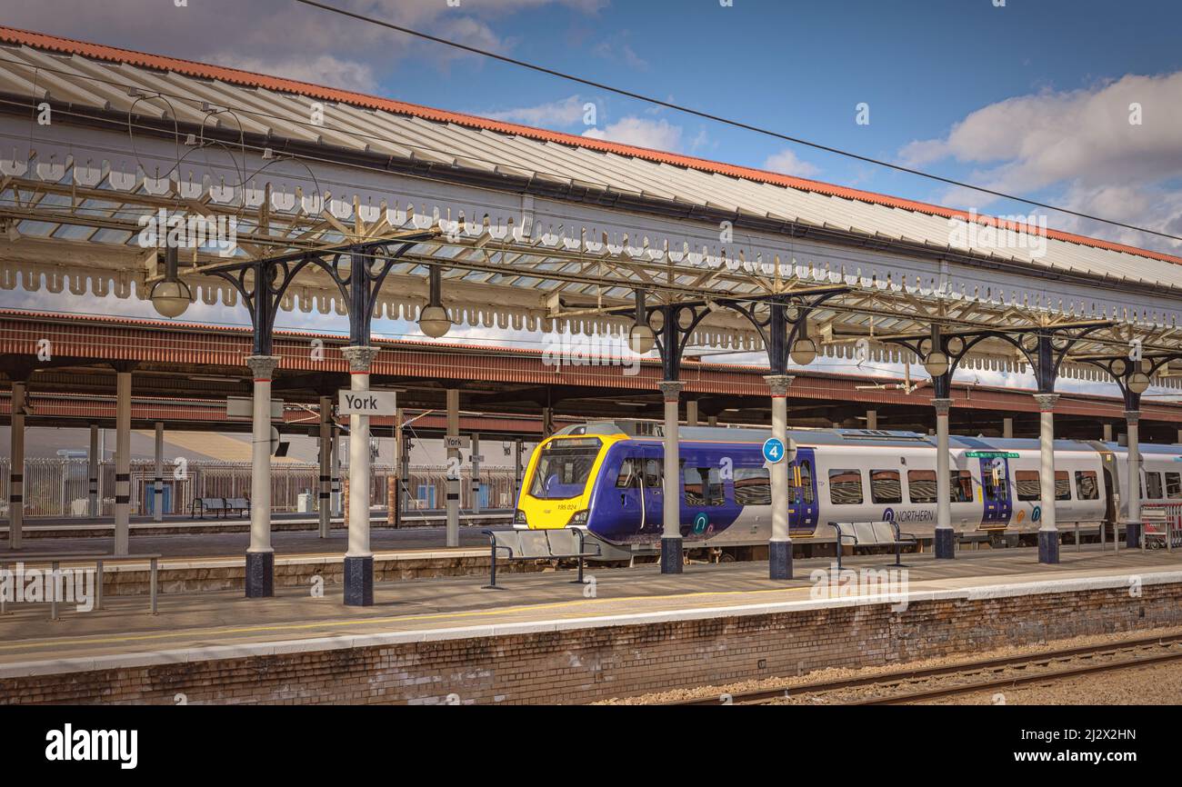 Railway station platform with a train alongside. Overhead is an ...