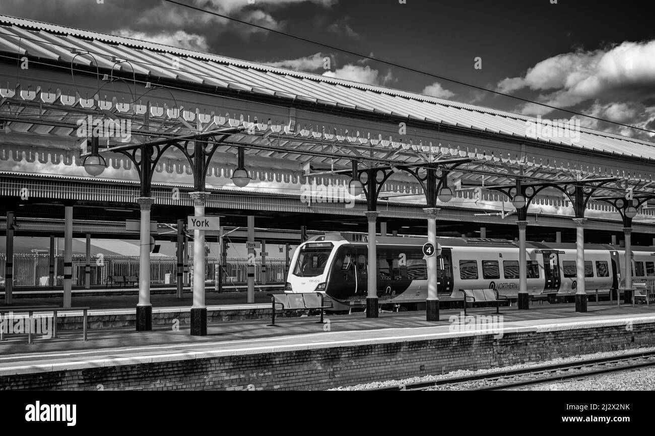 Railway station platform with a train alongside. Overhead is an ...