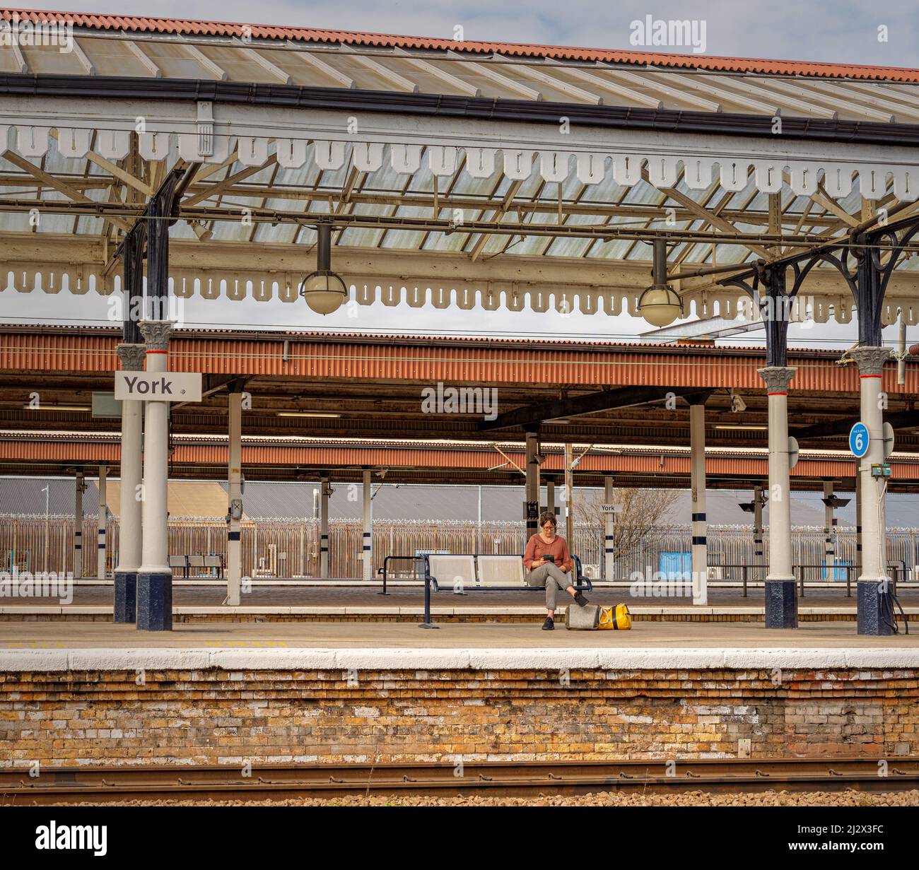 Railway station platform with passengers sitting and waiting for a ...