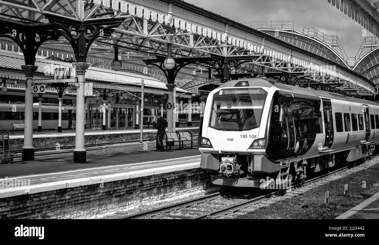 Railway station platform with a train alongside. Overhead is an ...