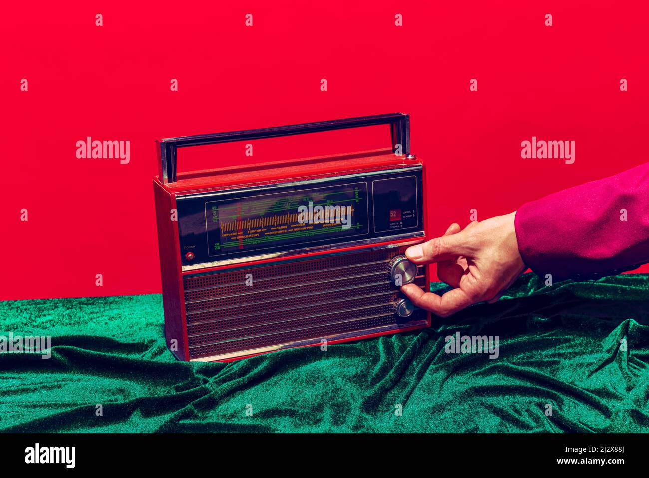 Retro radio. Female hand touching radioreceiver isolated on red and ...