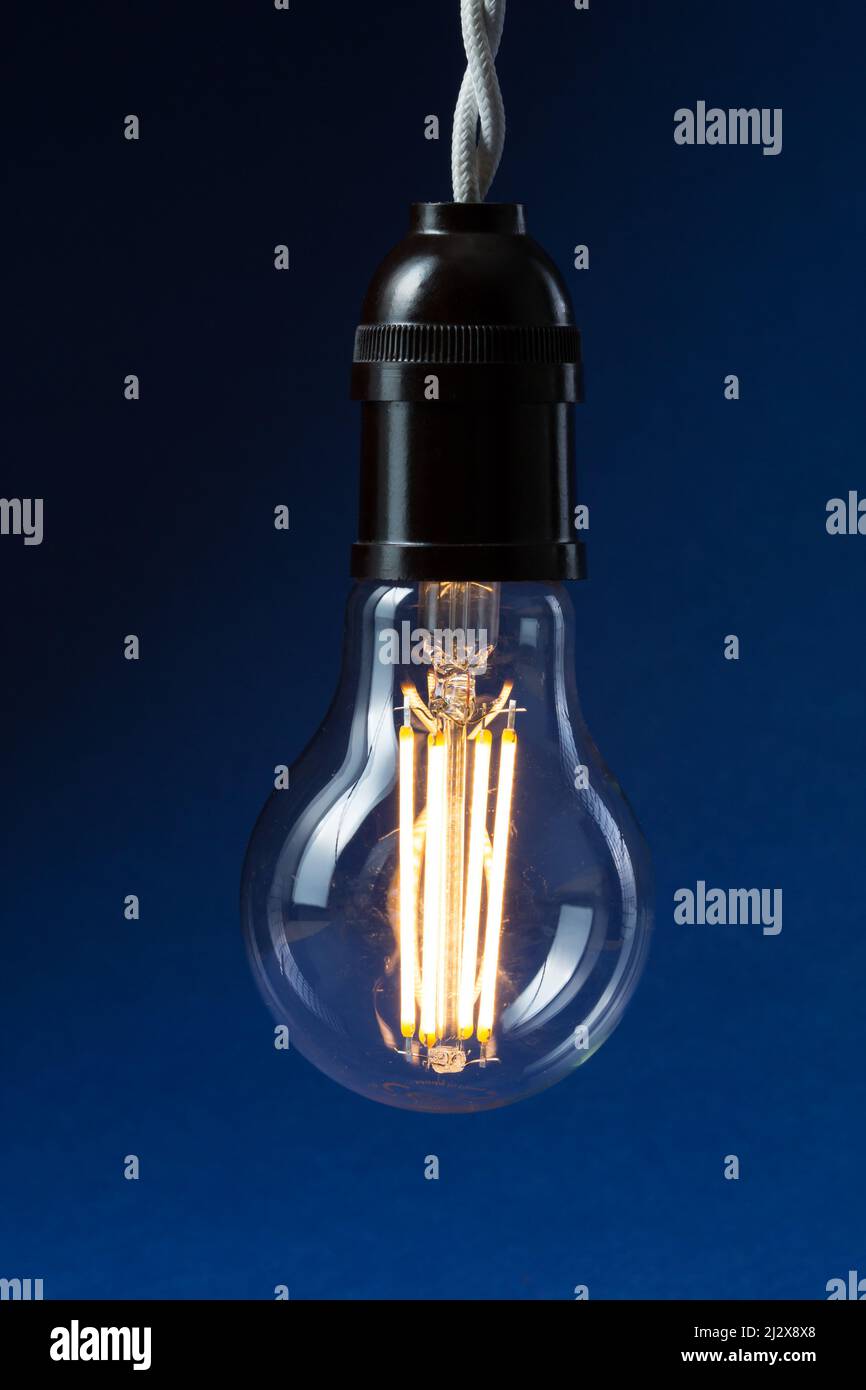 A vertical closeup of a new generation led light bulb on a blue ...