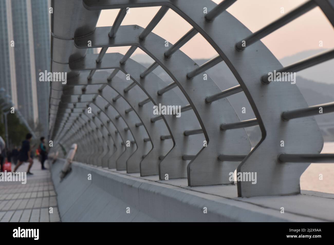 A side shot of the metal bridge with people standing and a rail ...