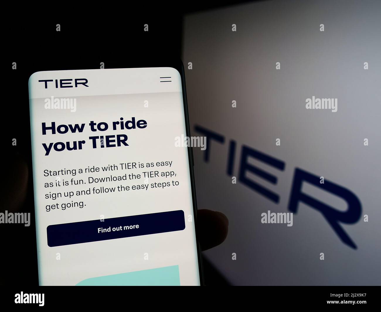 Person holding cellphone with webpage of German scooter company TIER ...