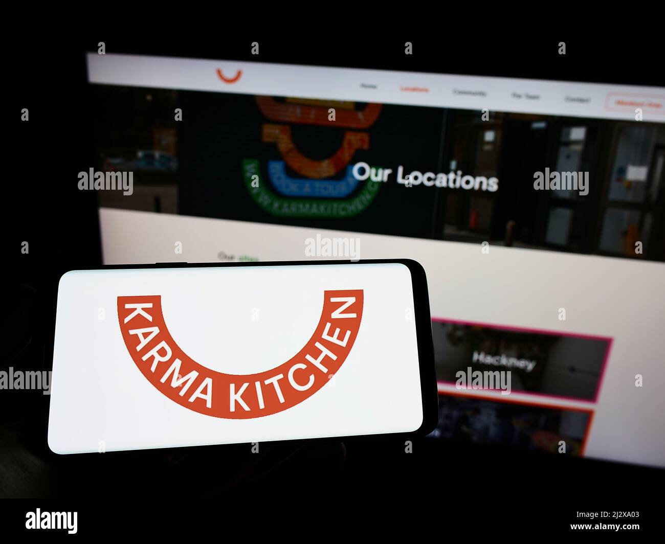 Person holding mobile phone with logo of British kitchen company Karma ...