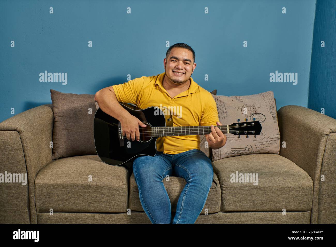Singing and playing guitar at home on a relaxed couch Stock Photo - Alamy