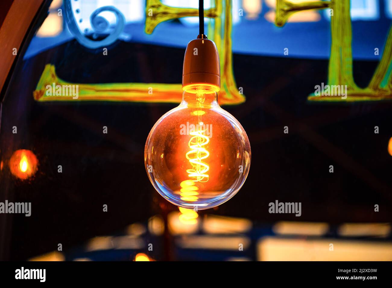 A large round Incandescent light bulb yellow warm color lamp hangs on ...