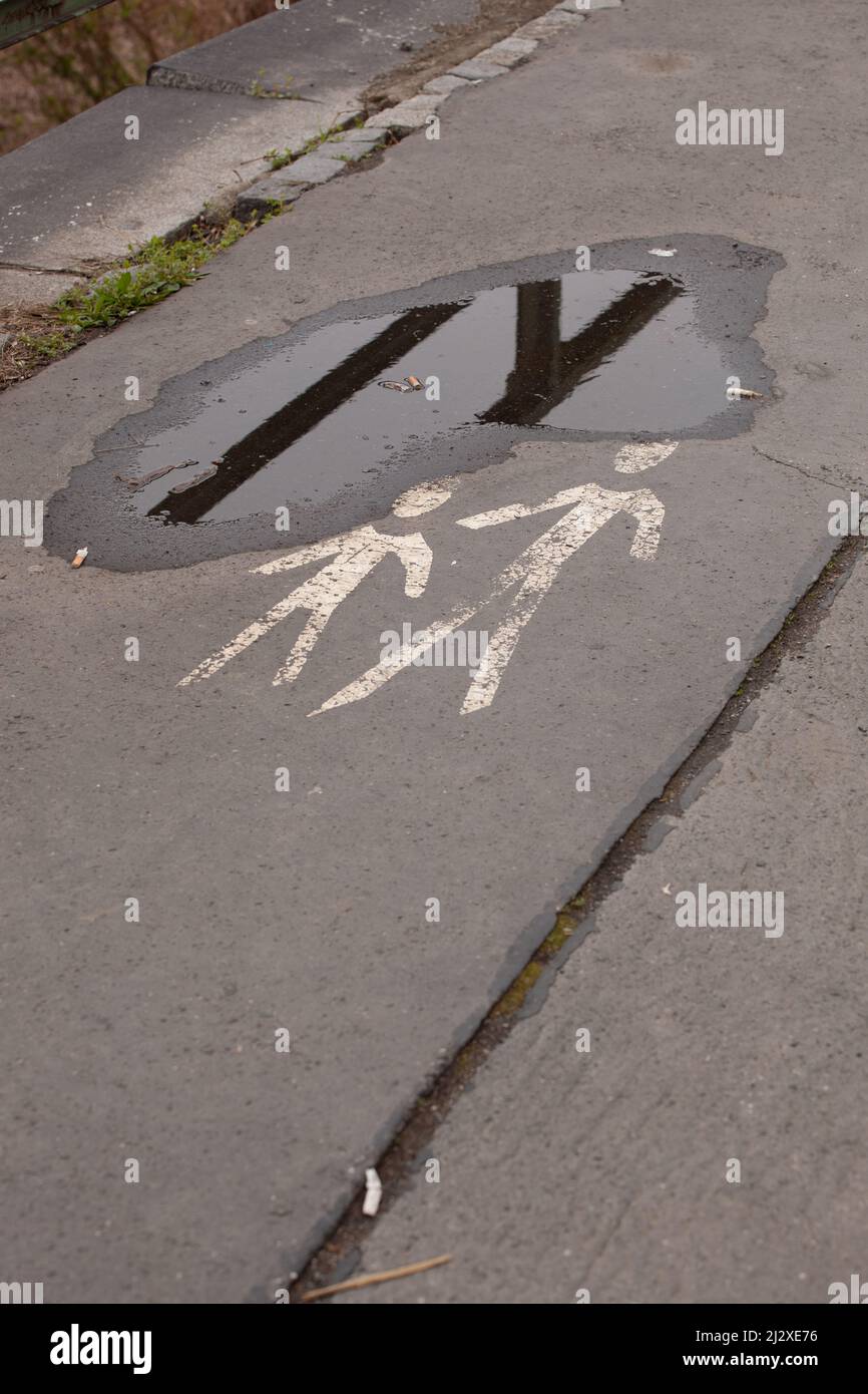 The sign symbolizing a pedestrian path is painted white on the black ...