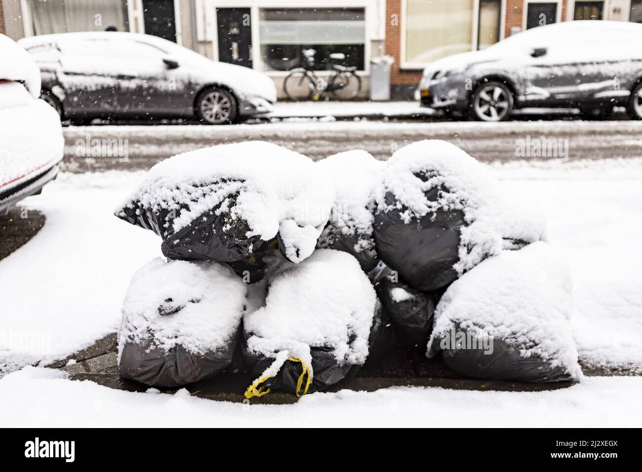 Plastic waste bags in street covered with a thick pack of snow in ...