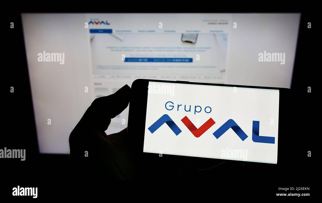 Person holding mobile phone with logo of Colombian Grupo Aval Acciones ...