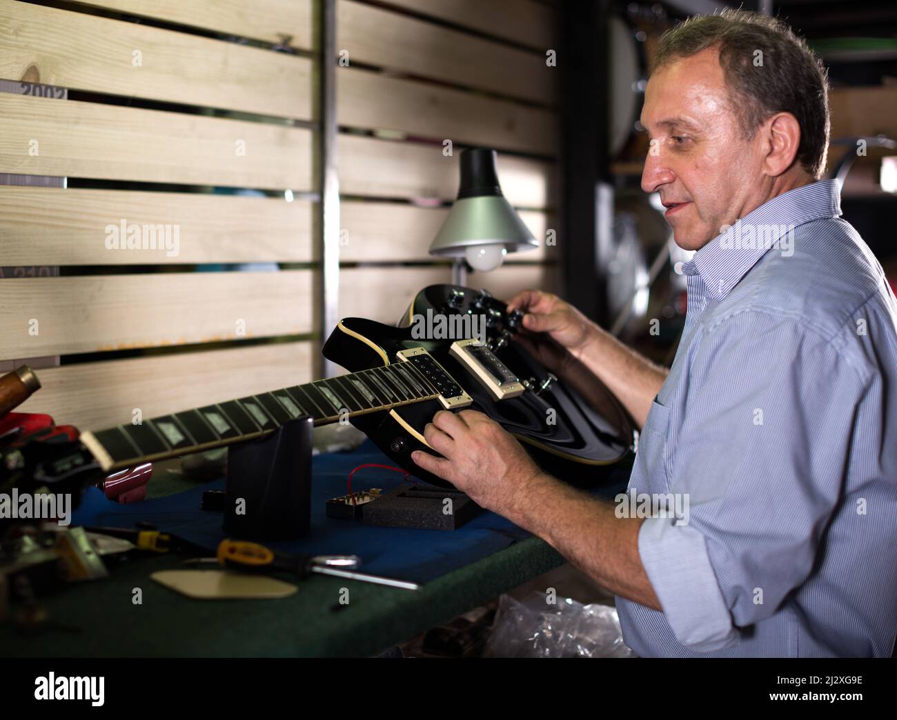 Adult guitarist is repairing his guitar in music studio Stock Photo - Alamy