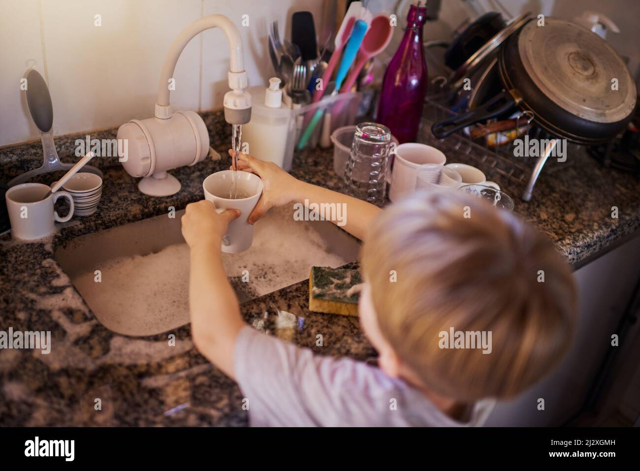 Chores are a vital life skills for kids to learn. High angle shot of a little boy washing dishes ...