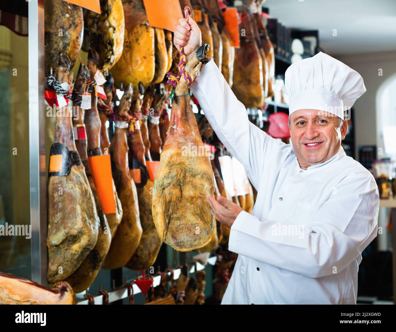 Portrait of cheerful smiling positive mature shop man offering Spanish ...