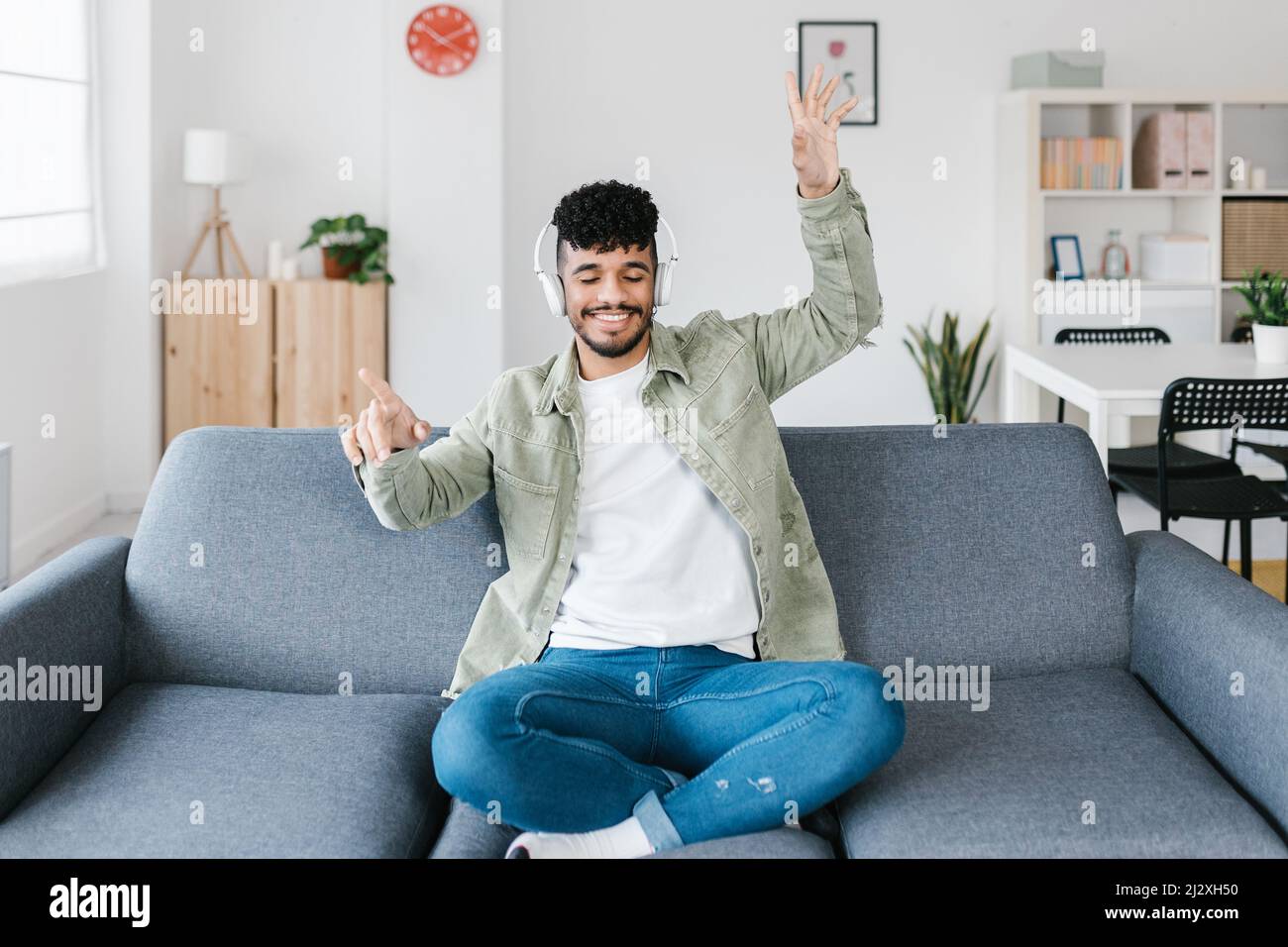 Man wearing headphones listening music and dancing while sitting on ...
