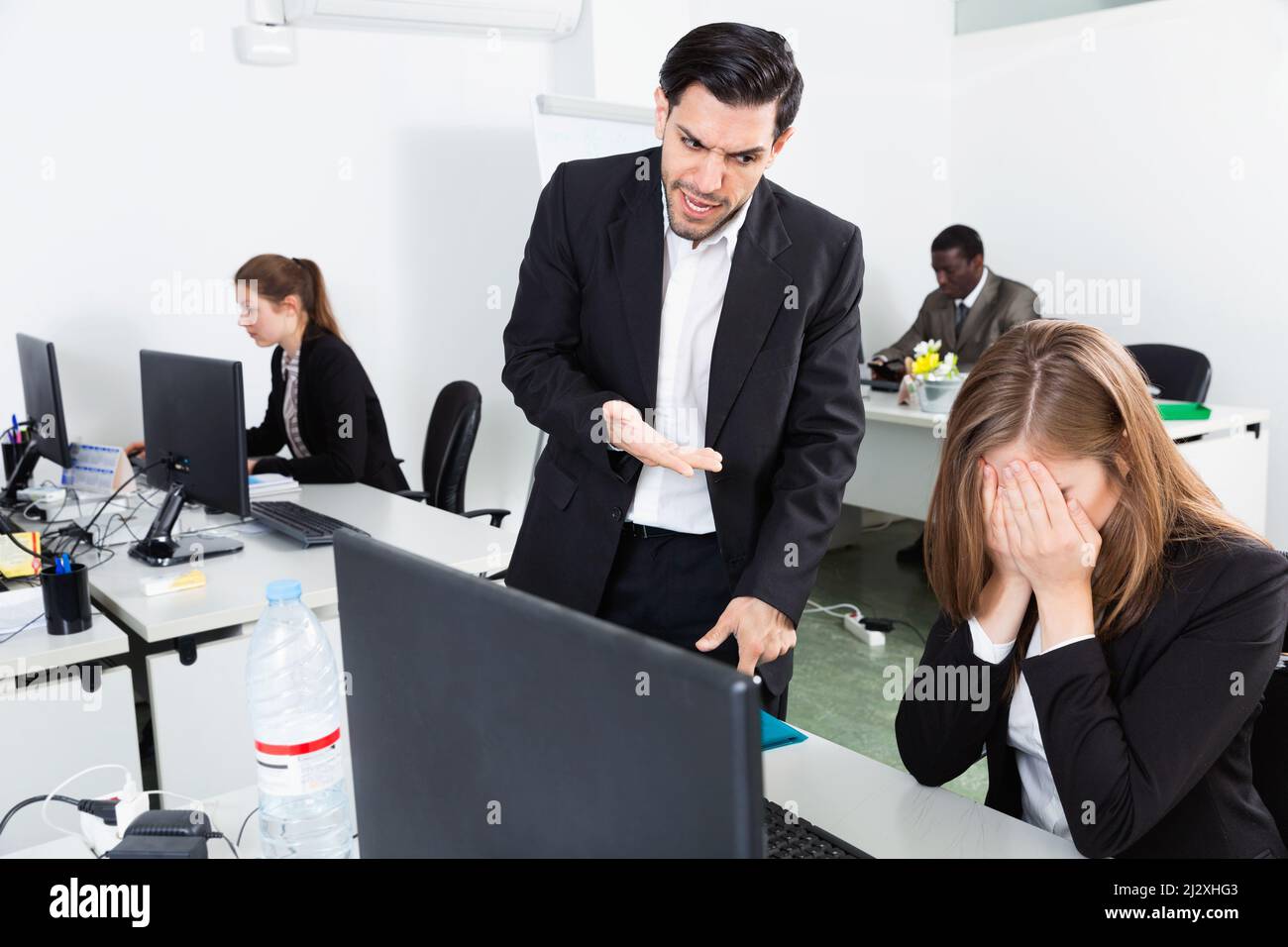 Unhappy tired woman manager working at laptop and angry man boss ...