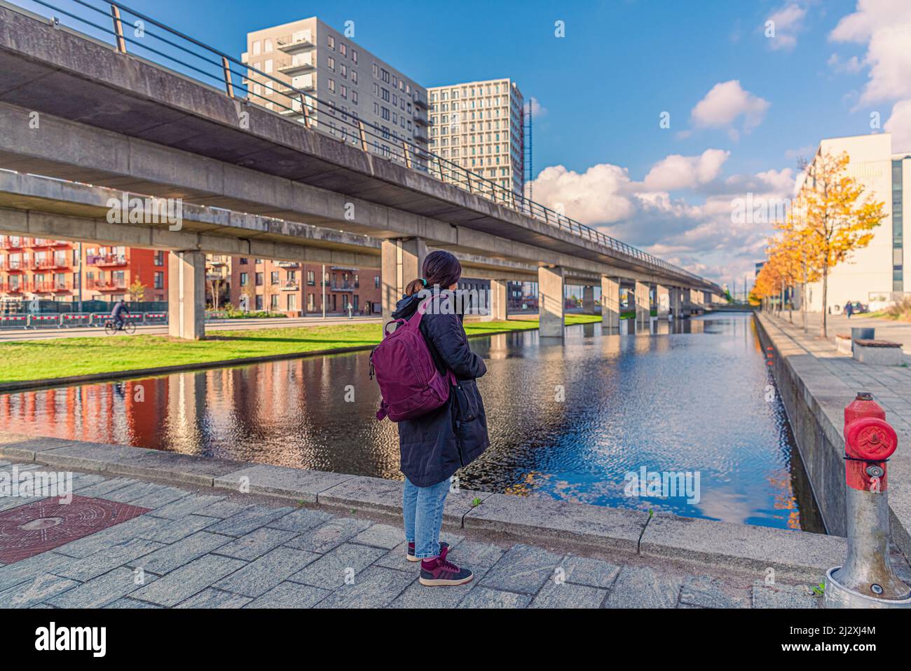 A black-haired woman in warm clothes stands near a fire hydrant and ...
