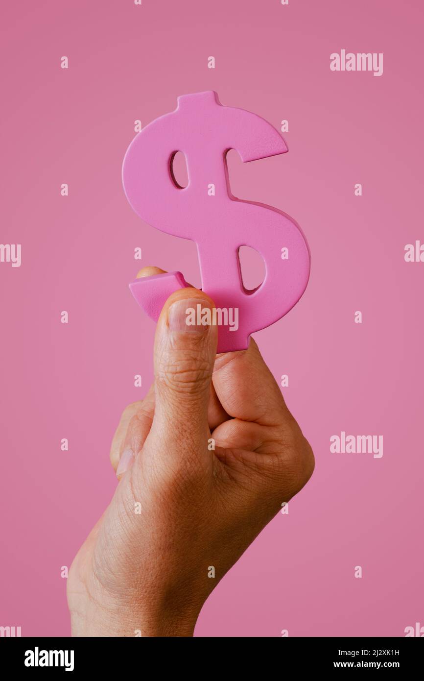 closeup of a young man grabbing a pink dollar sign on a pink background ...