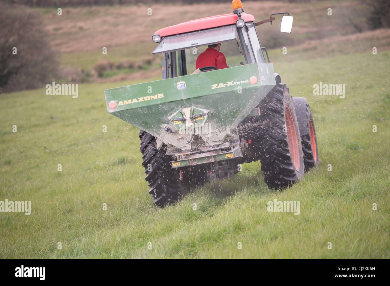 Farmer spreading artificial fertiliser on grass field Stock Photo - Alamy