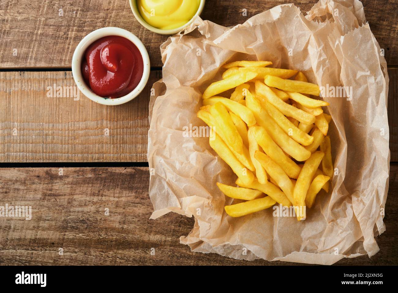 French fries. Tasty French fries server on parchment paper on wooden ...