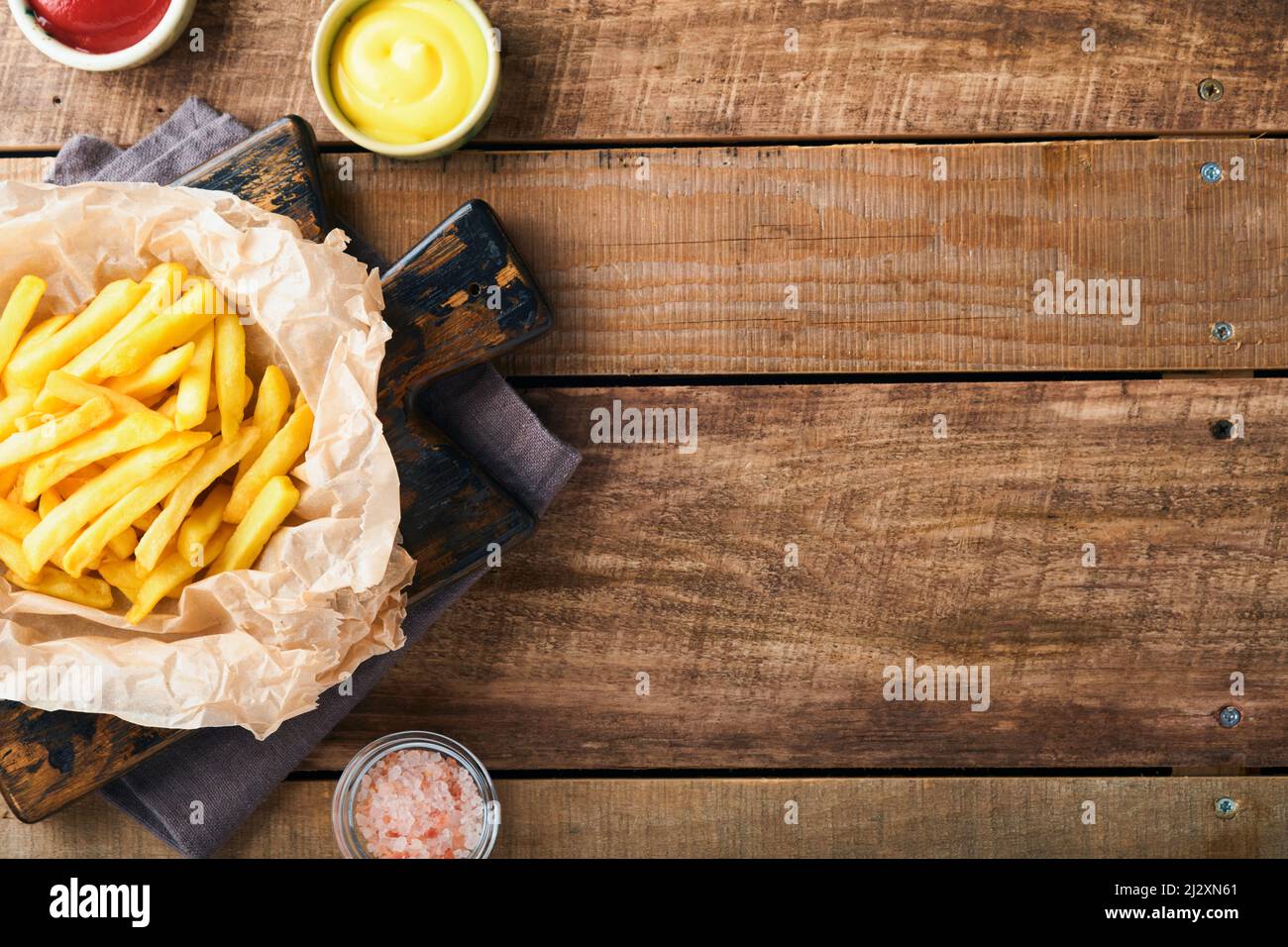French fries. Tasty French fries server on parchment paper on wooden ...