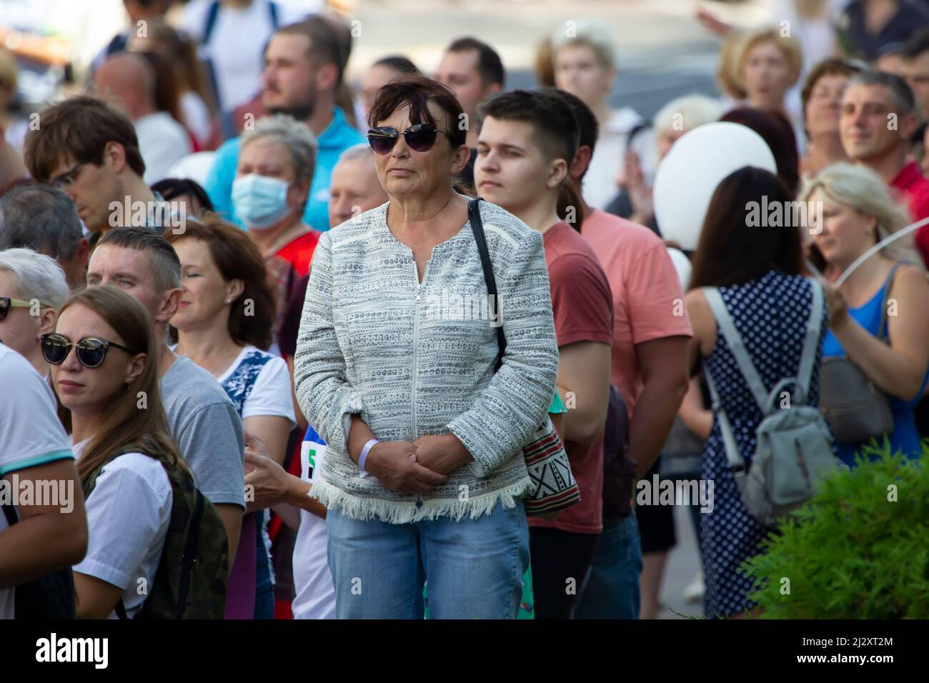 An elderly woman stands in a crowd of people Stock Photo - Alamy