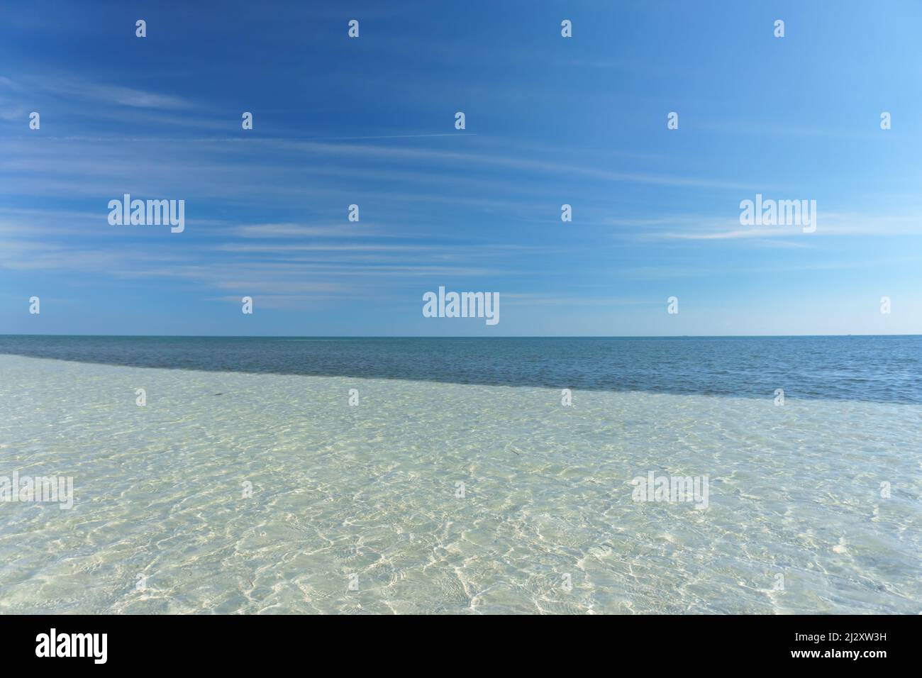 A beautiful view of the calm ocean gleaming under the cloudy blue sky ...