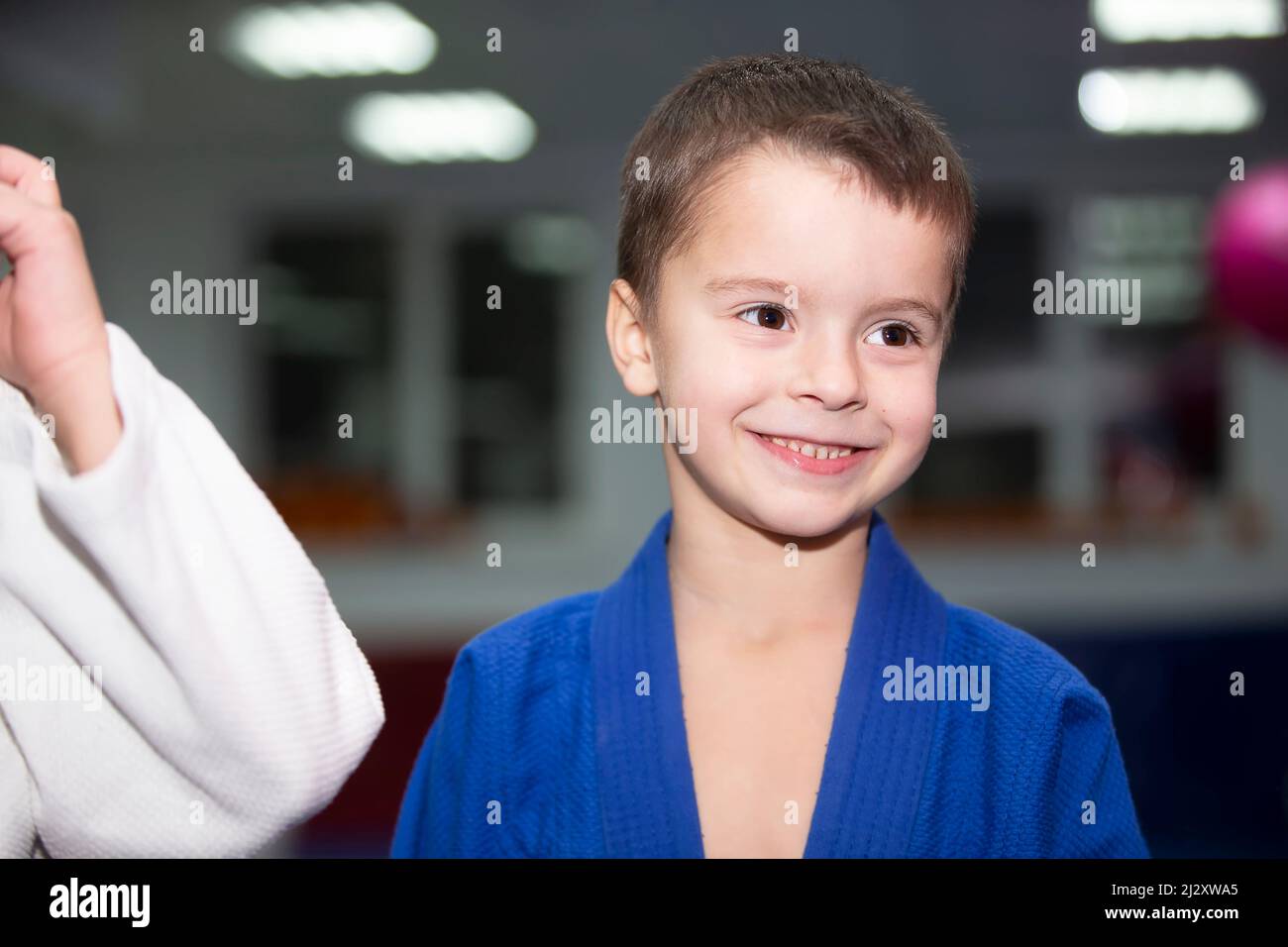 Judo school for children. A little boy in a kimano smiles in training ...