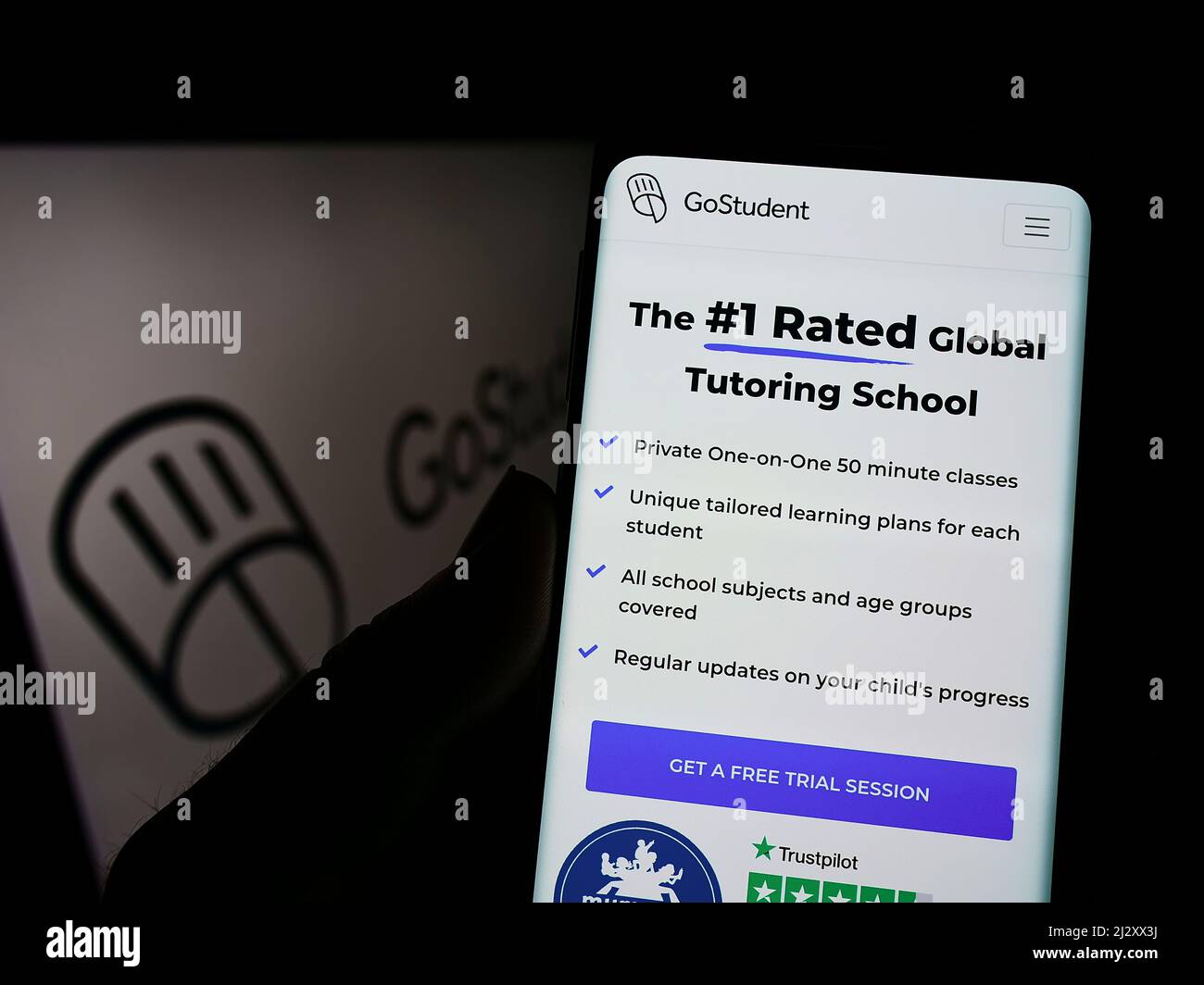 Person holding cellphone with webpage of Austrian tutoring company ...