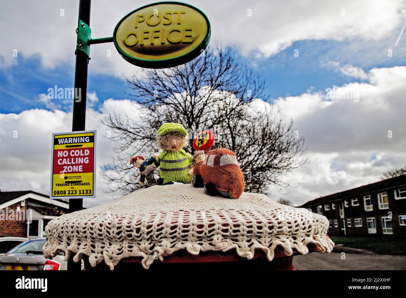 A hand-knitted/crocheted woollen cover placed on top of a royal Mail ...