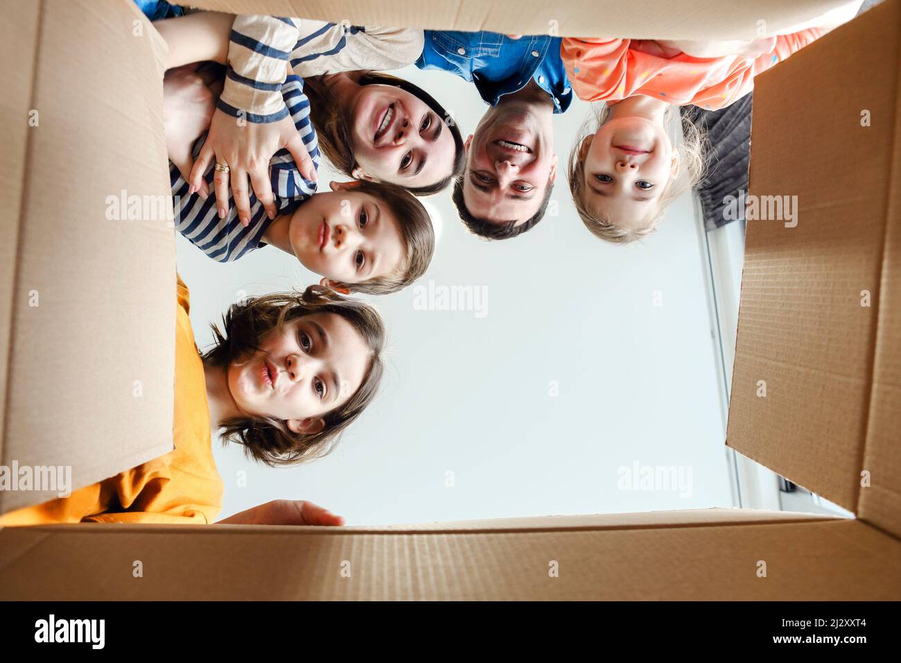 Happy family of five looking into cardboard box. Young family peeking ...