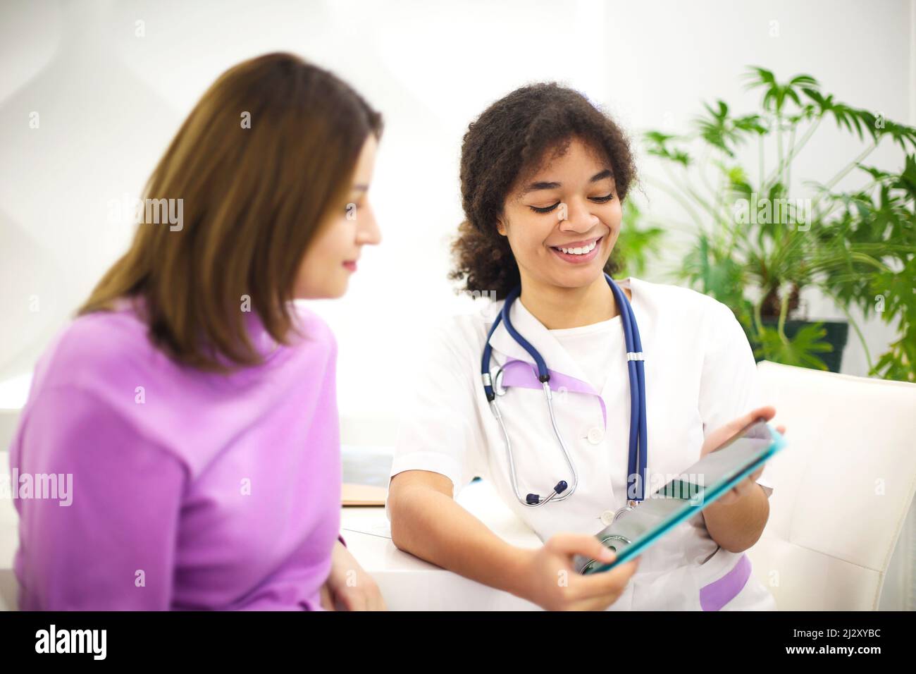 Beautiful young mixed race female doctor with pregnat patient sitting ...