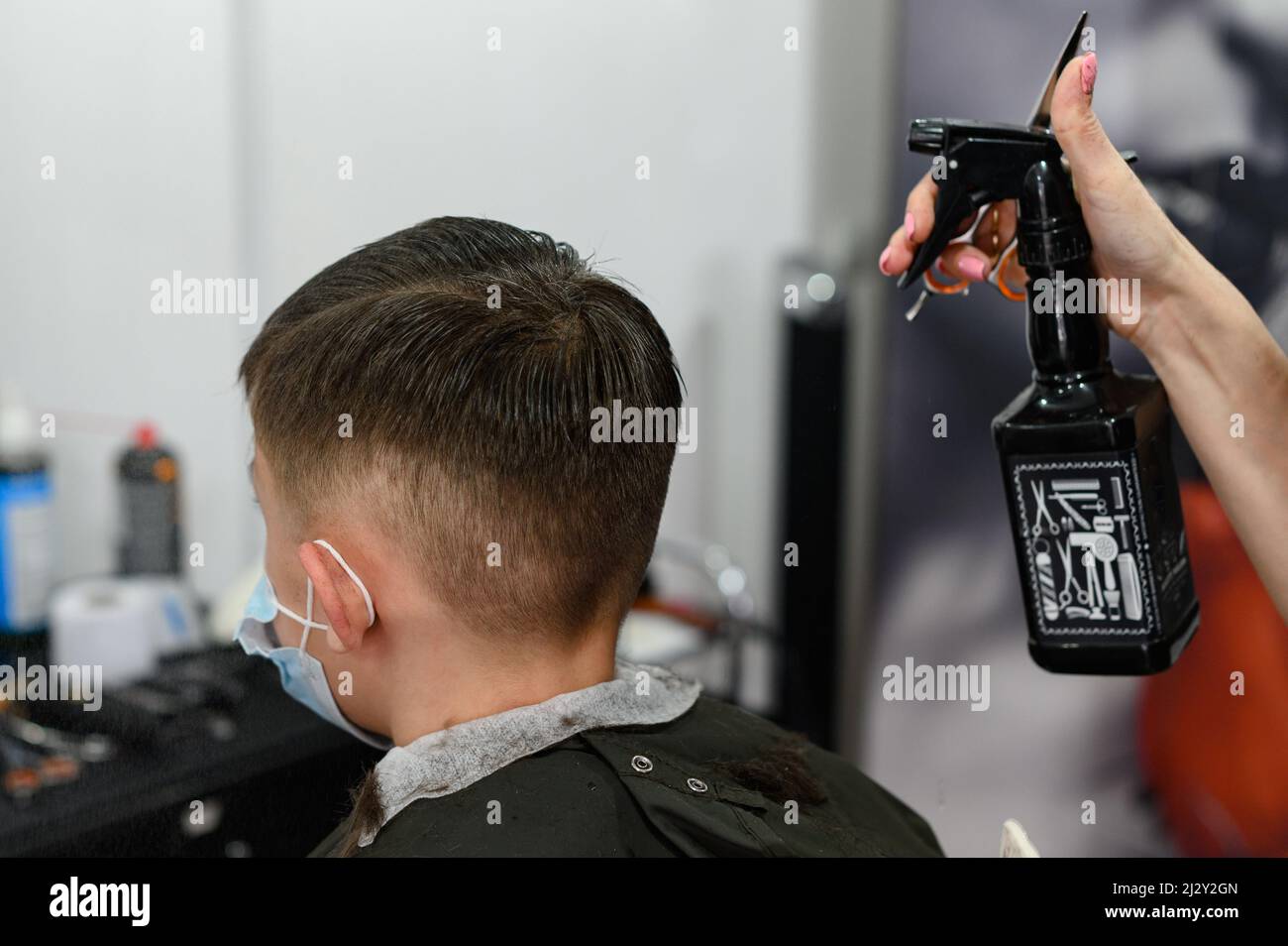 A teenager in a beauty salon gets a haircut, a hairdresser cuts a teen ...