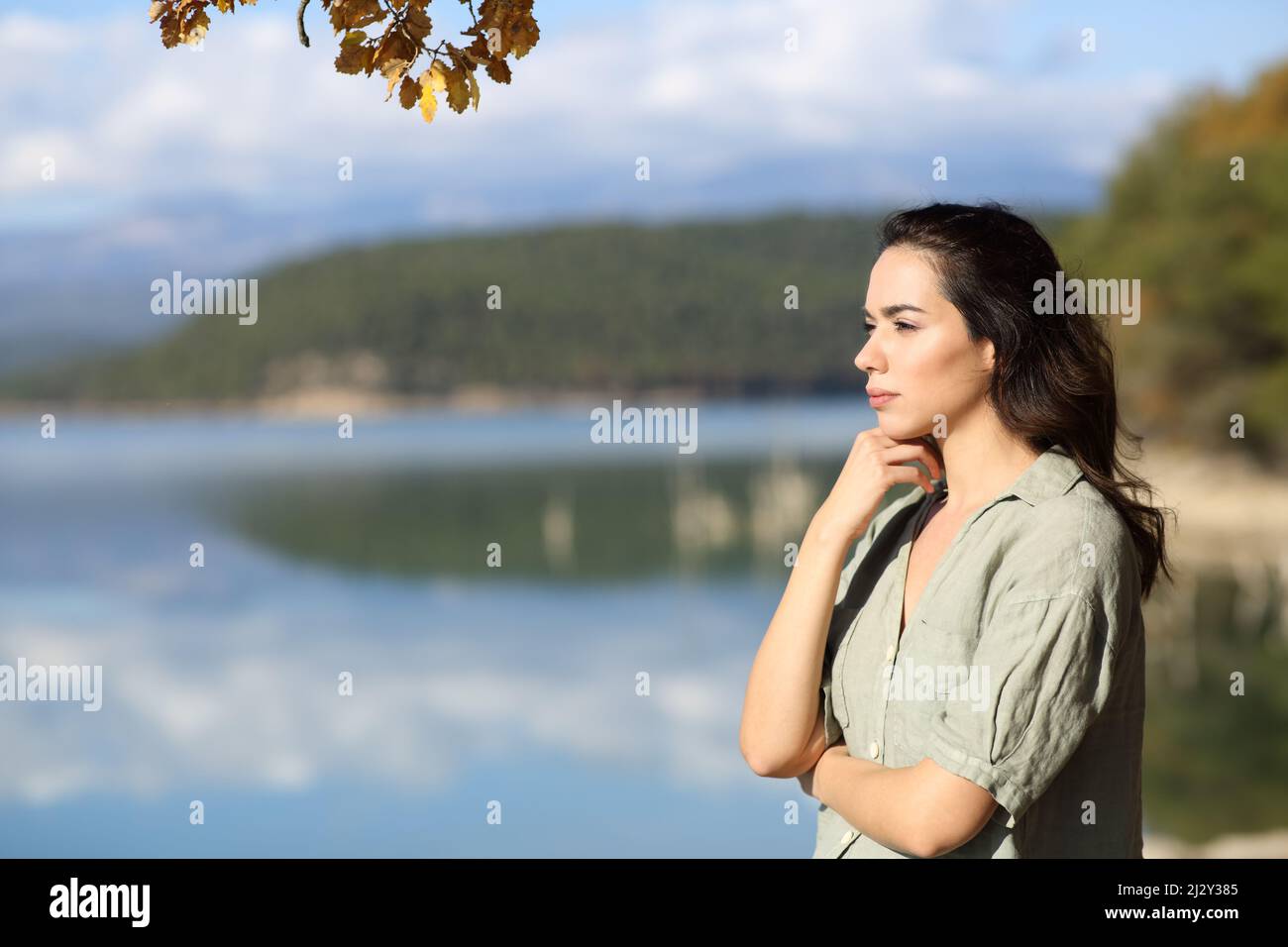 Side view portrait of a relaxed woman contemplating views in a lake ...