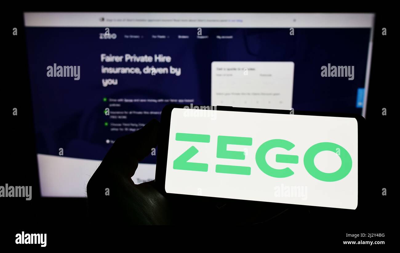 Person holding cellphone with logo of British insurance company Extracover Limited (Zego) on ...