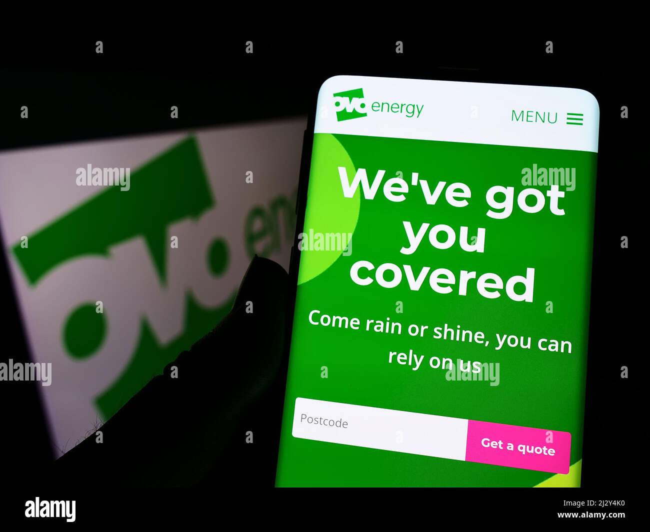 Person holding cellphone with website of British utility company OVO ...
