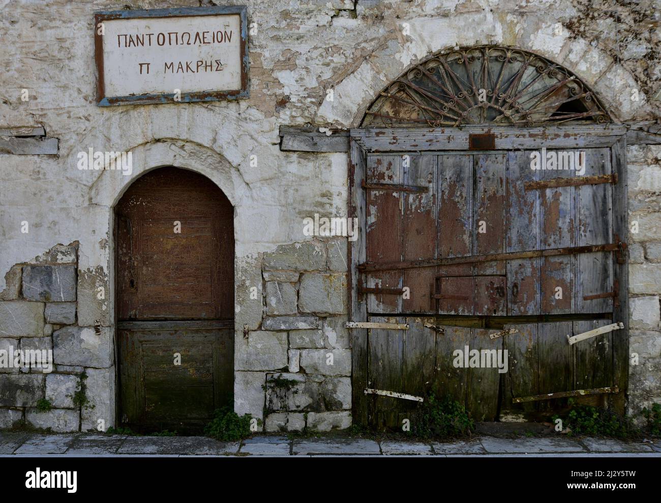 Old abandoned traditional local grocery store with a stone wall, arched ...