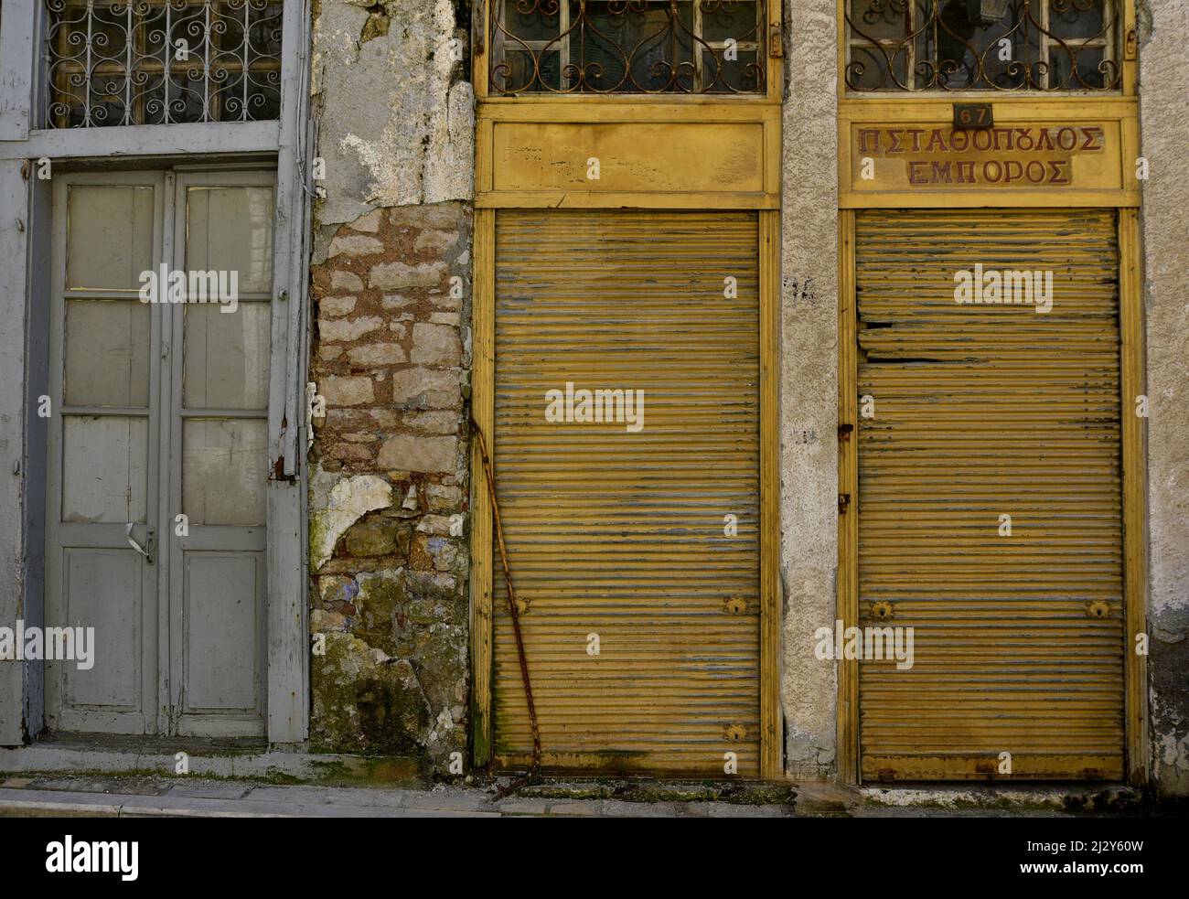 Old abandoned commercial store with faded walls, ochre wooden doors and ...