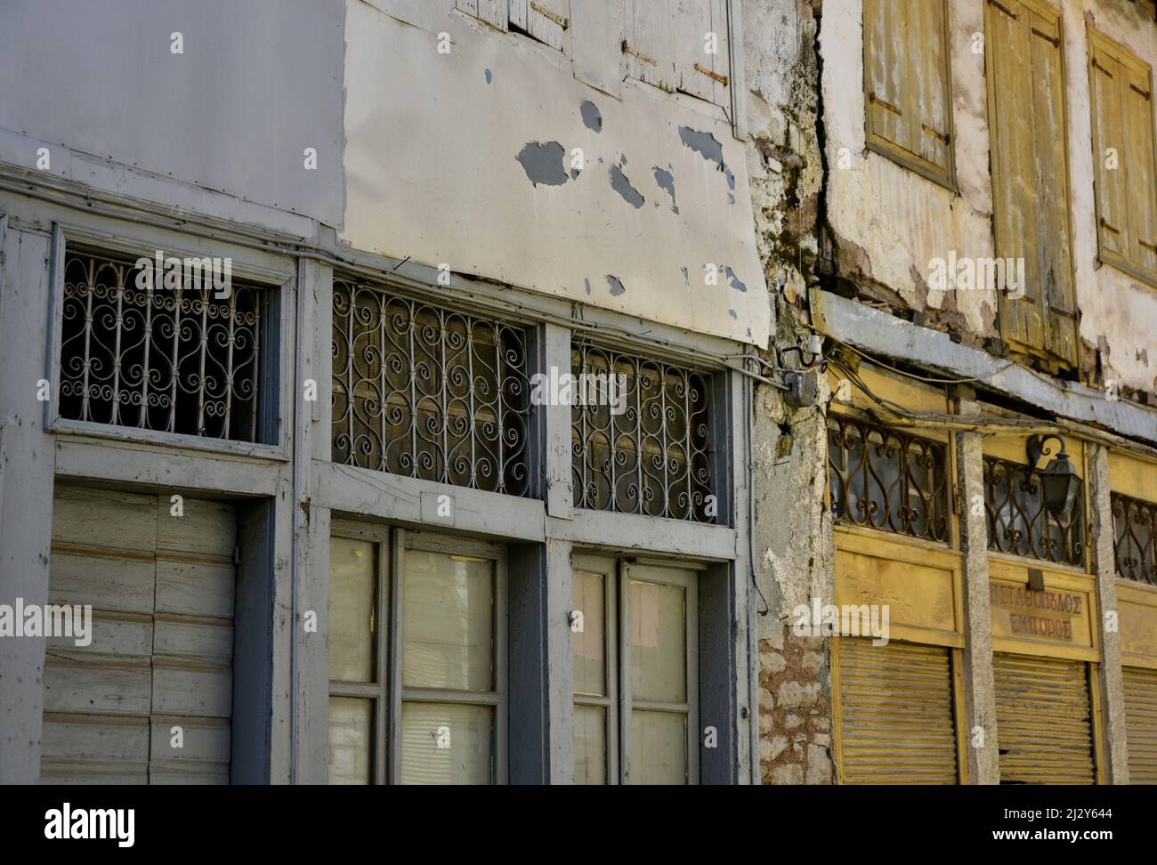 Old abandoned commercial store with faded walls, ochre wooden doors and ...