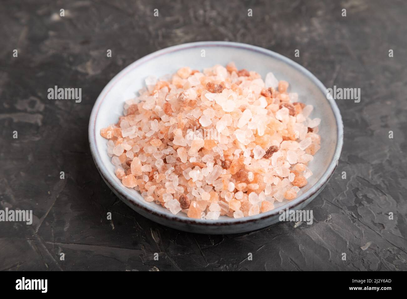 plate with pink Himalayan salt on black background Stock Photo - Alamy