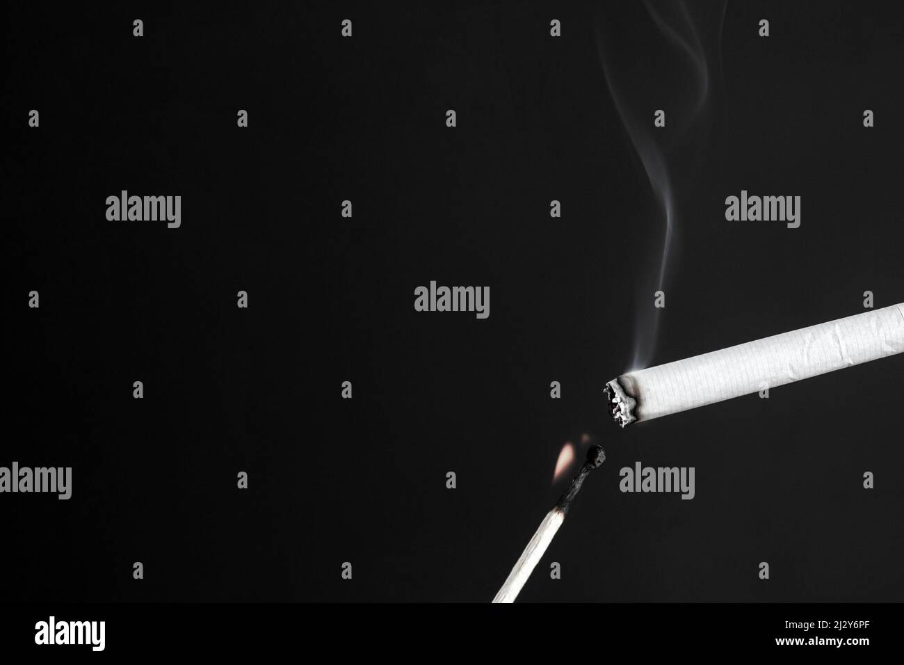lighting a cigarette with a burning match on dark background Stock ...
