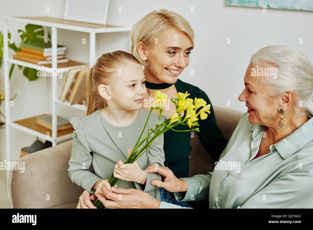 Portrait of little girl giving flowers to grandmother on Mothers day ...