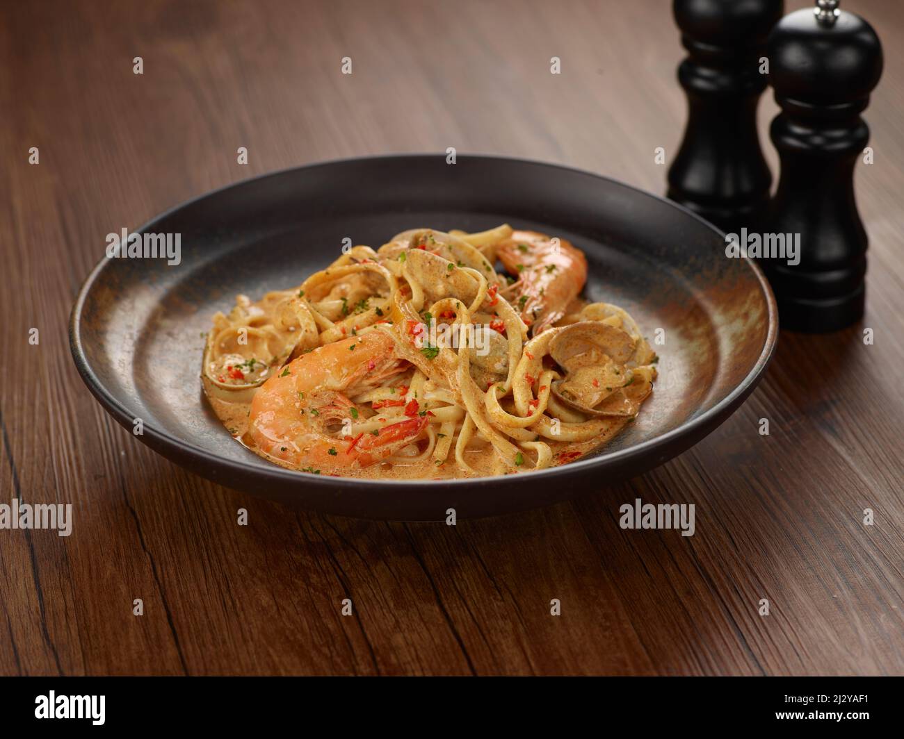 Tom Yam Seafood Pasta a dish isolated on dark wooden table side view ...