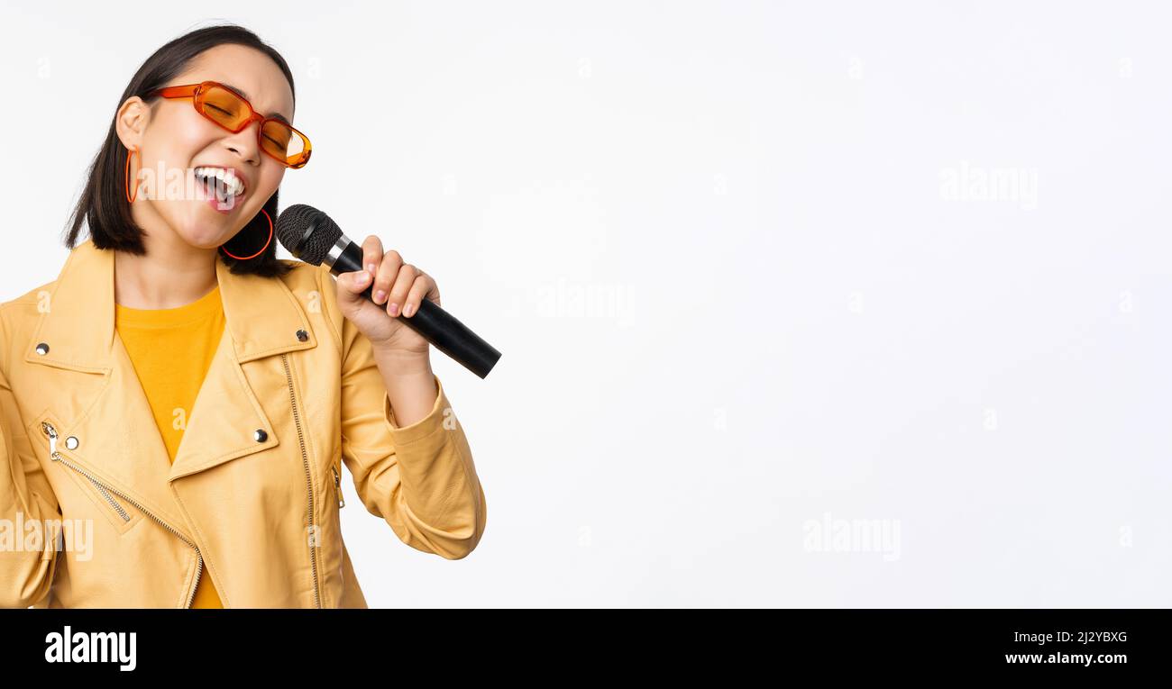 Singing girl holding microphone, performing songs at karaoke, standing ...