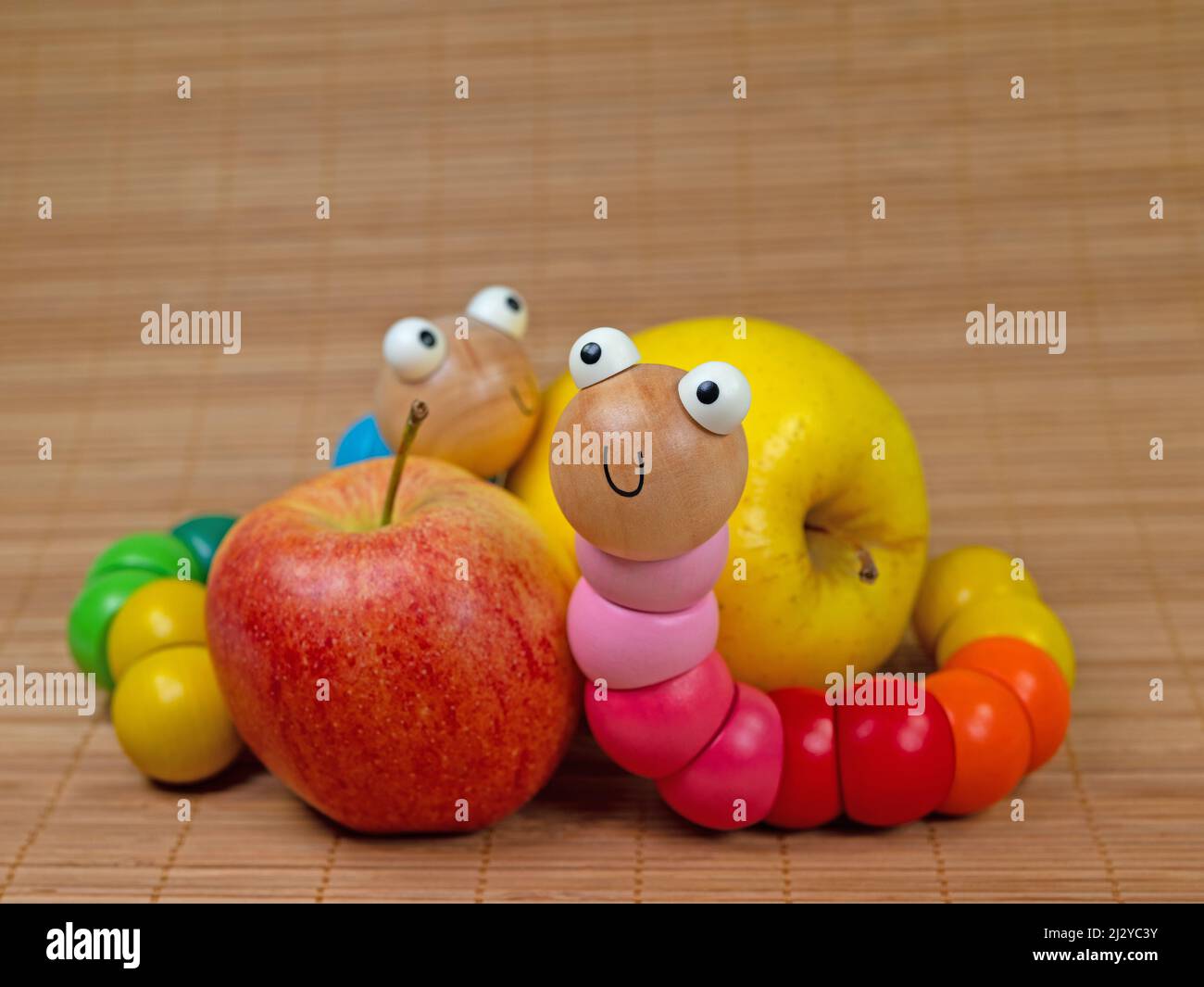 Wooden toy worms in front of apples Stock Photo - Alamy