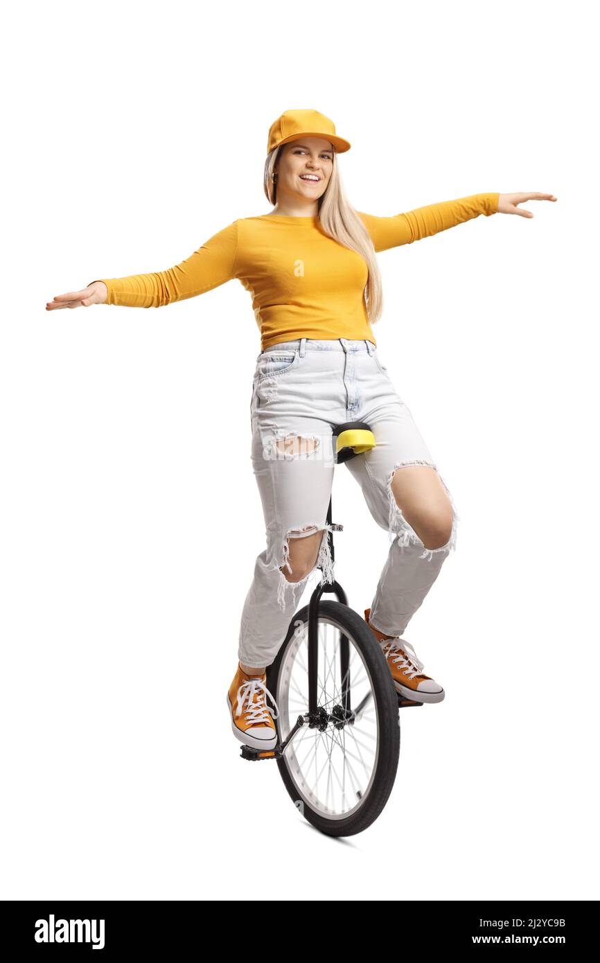 Young female riding a unicycle and smiling isolated on white background ...