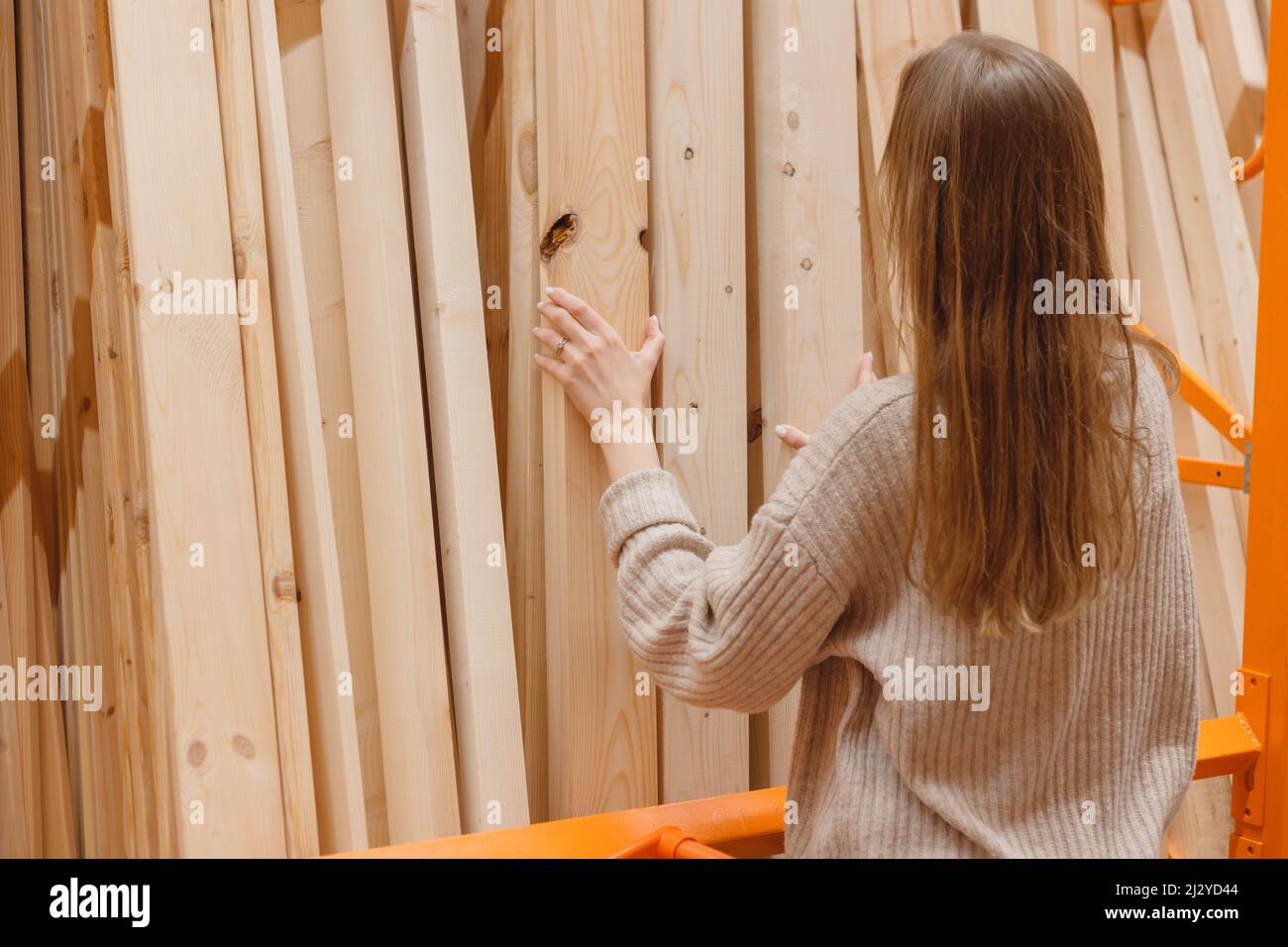 Woman choosing wooden plank in hardware store. Building materials for ...