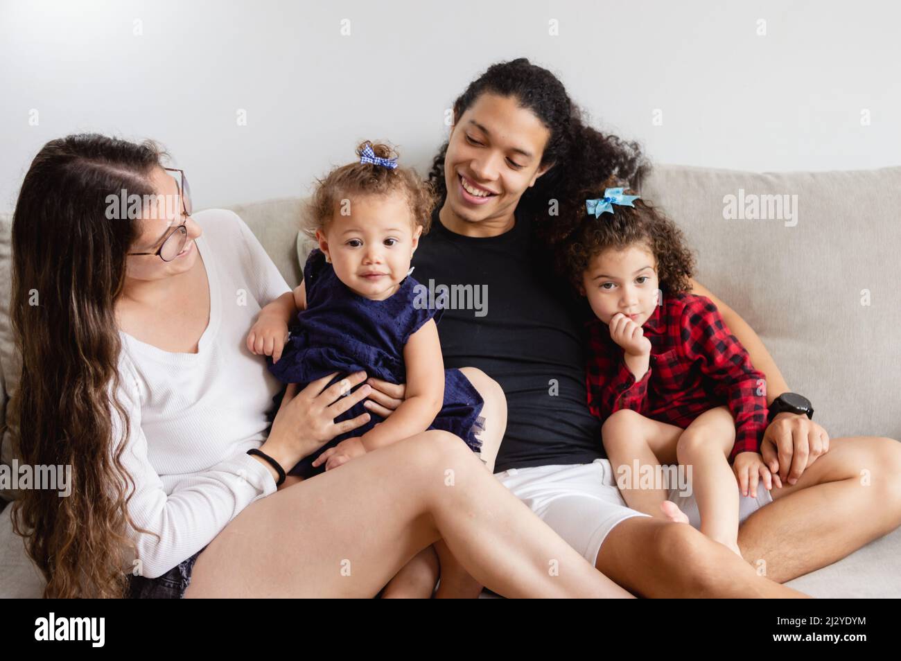 beautiful caucasian baby with curlers looking at the camera on the sofa ...