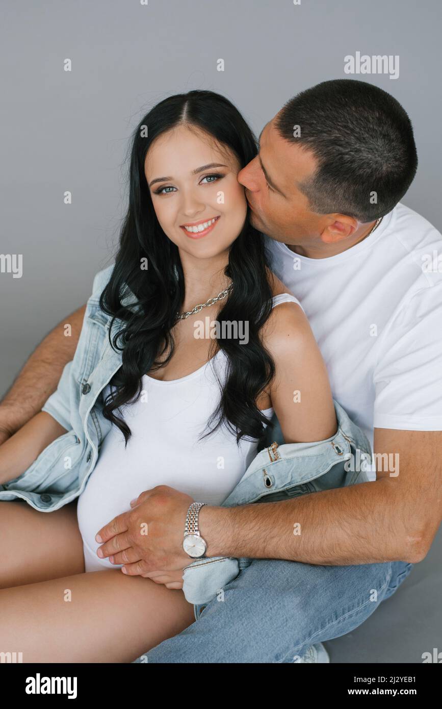 A Happy Man Hugs His Pregnant Girlfriend And Looks Into The Camera Loving Husband Gently Kisses